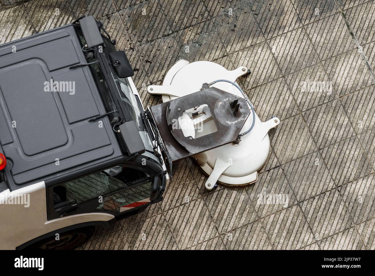 A street washer machine cleaning dirty pavement with water. View from ...