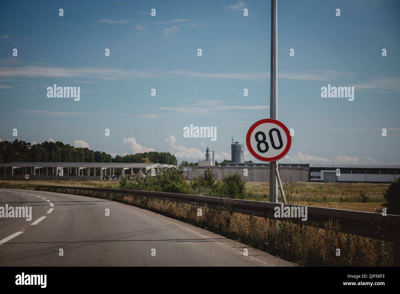 An asphalt road with a speed limit sign on the side during daytime ...