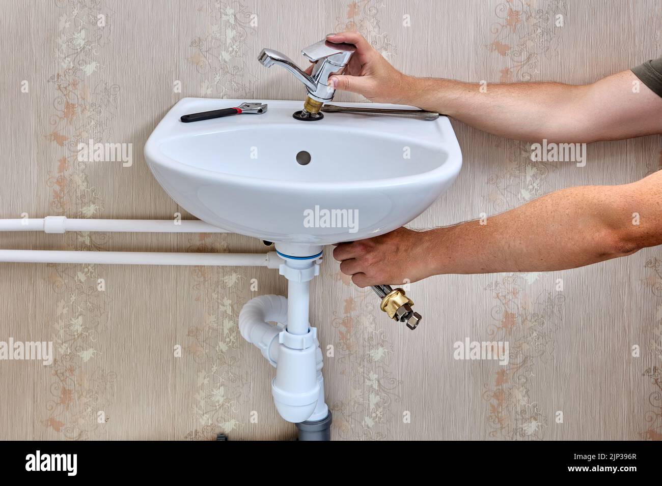 Installing single lever faucet on washroom sink, plumber inserts water ...