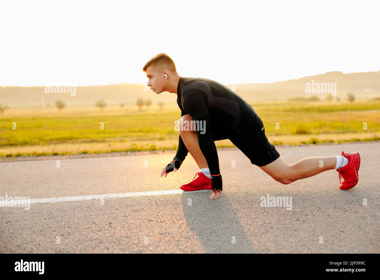 Close-up of male crouch start on asphalt track outside and turning back ...