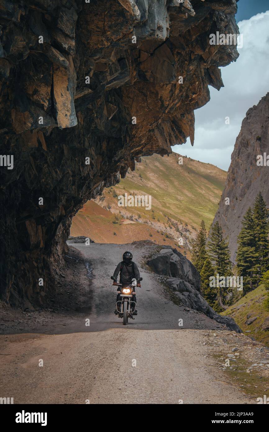 A vertical shot of a motorcyclist with helmet riding a bike on a road ...