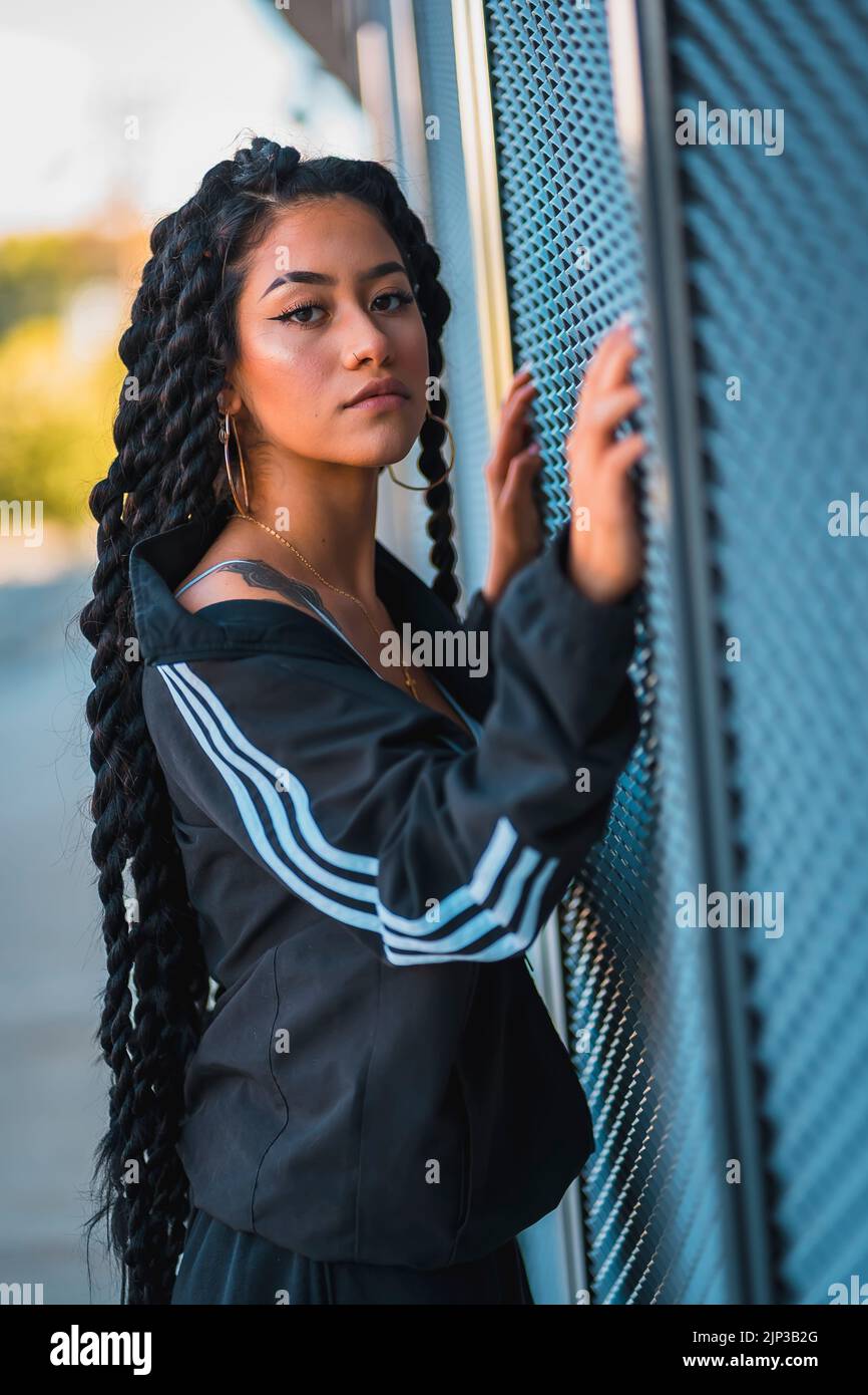 A Hispanic woman with long braids in sportswear Stock Photo - Alamy