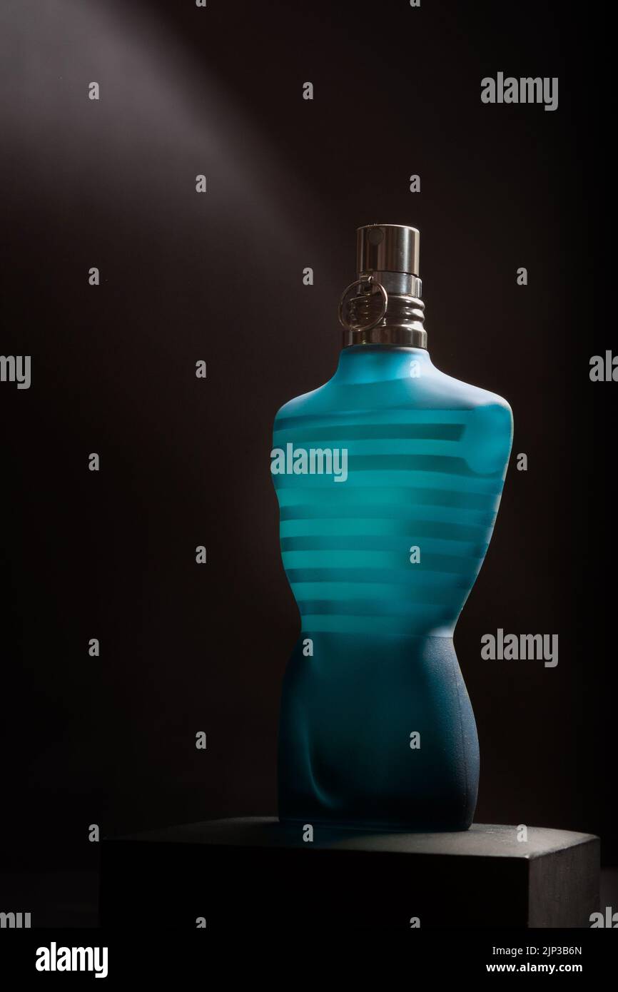 A vertical closeup of a blue bottle design of a perfume on a dark ...