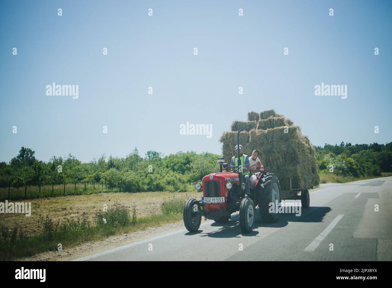 A view of a man riding loaded tractor on road in the countryside Stock ...