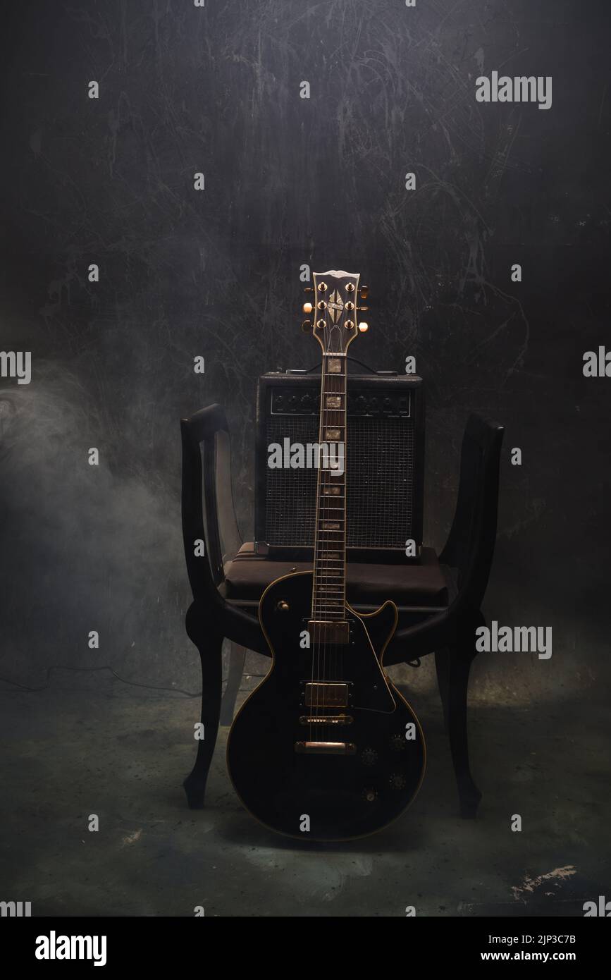 A black electric guitar on a chair Stock Photo - Alamy
