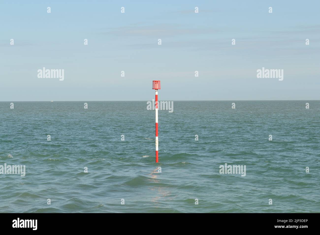 A small red and white navigation beacon in the middle of the sea Stock ...