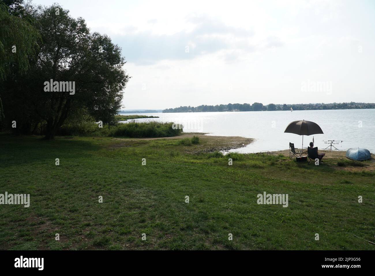 fisherman with umrella at lake Stock Photo - Alamy
