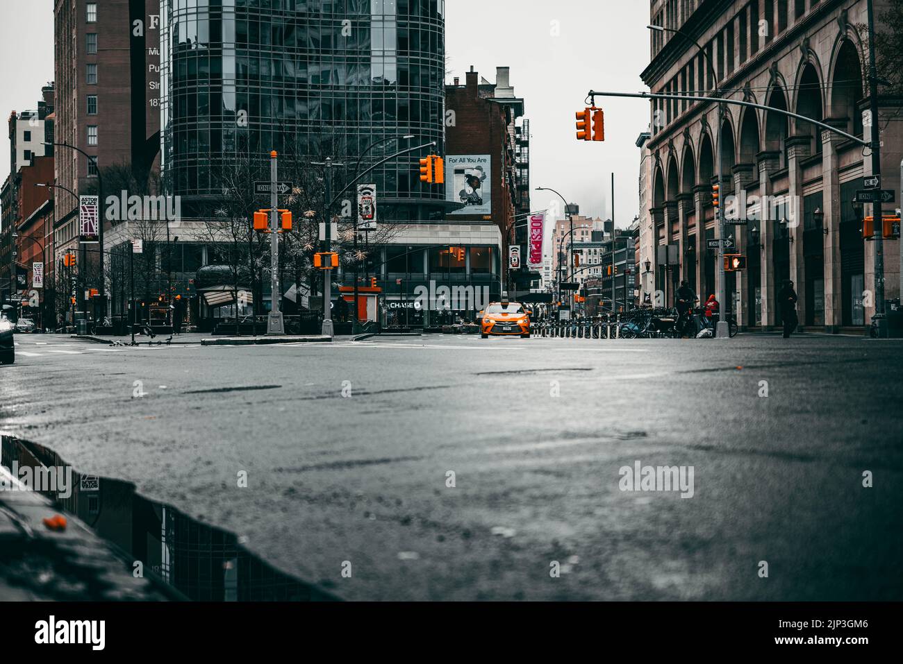 A landscape of an empty street surrounded by modern buildings in rainy ...