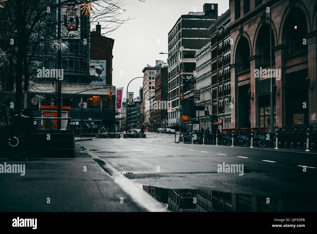 A landscape of an empty street surrounded by modern buildings in rainy ...