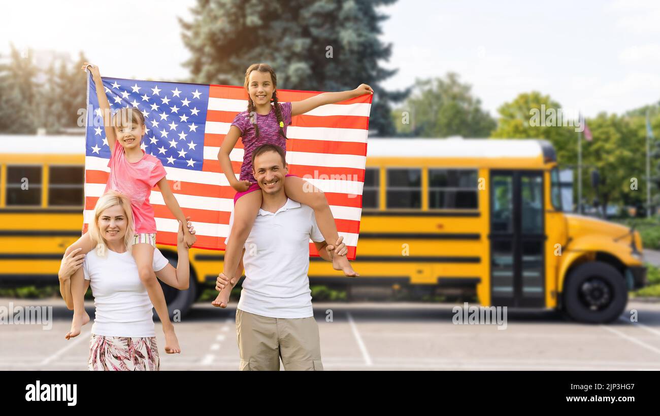 Happy young family with national flags of USA near the school bus Stock ...