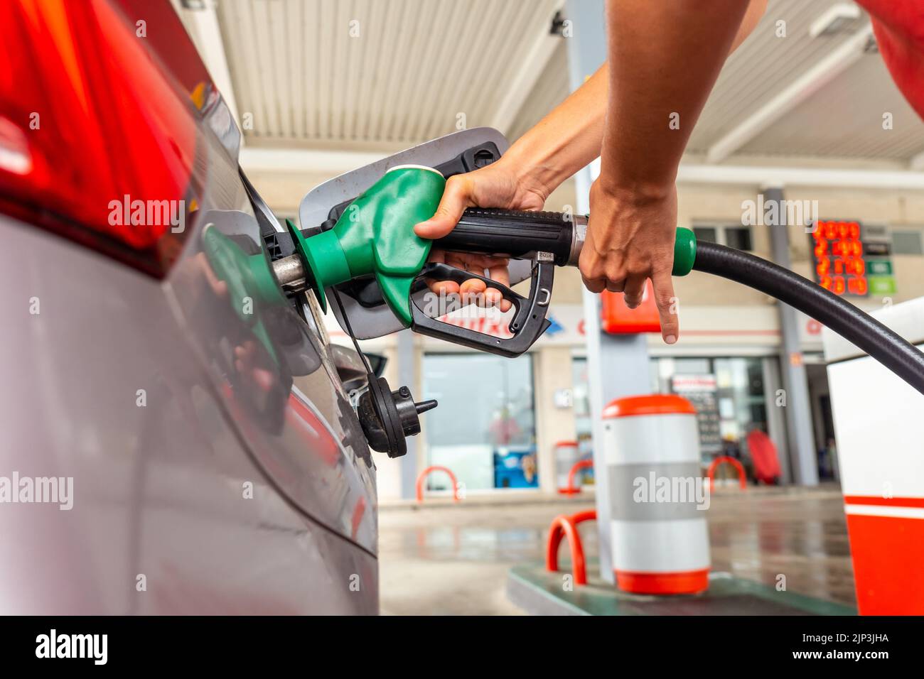 A closeup shot of a woman refueling her car with gasoline at a gas ...