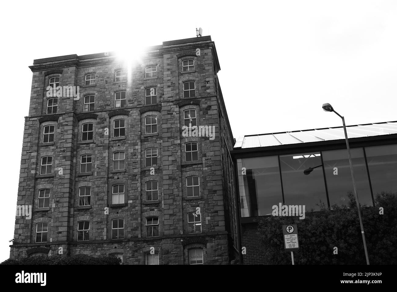 A grayscale of the sun shining behind an old stone building in Dublin ...