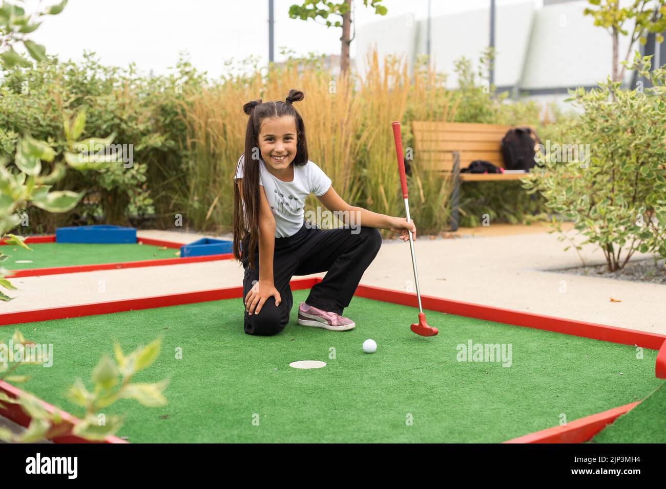 Miniature golf outdoor. Little caucasian girl golfing in the mini golf ...