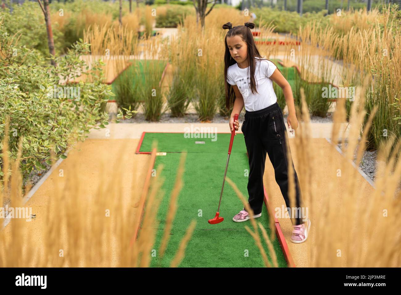 Cute preschool girl playing mini golf with family. Happy toddler child ...