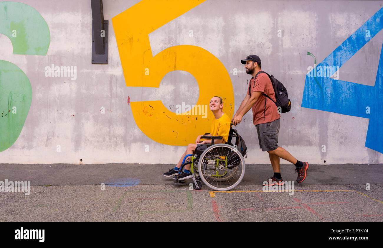 A disabled person in a wheelchair walking through the town square with ...