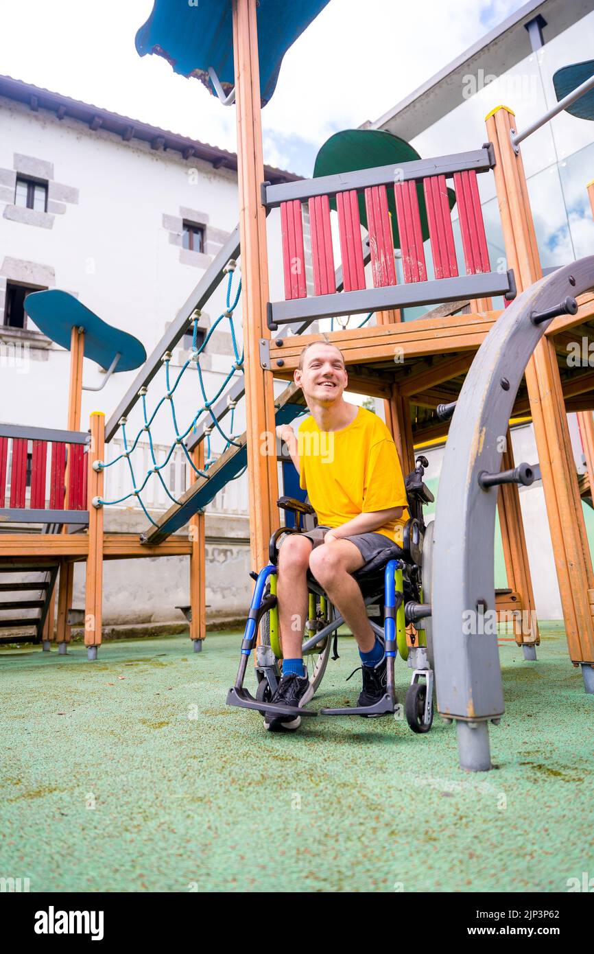 A disabled person in a wheelchair on the swings of a playground having ...