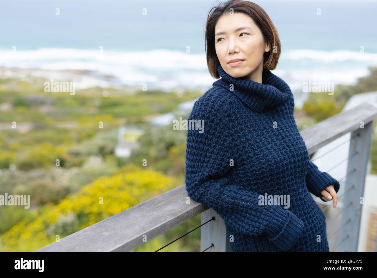 Asian woman wearing jumper and leaning on balcony alone Stock Photo - Alamy