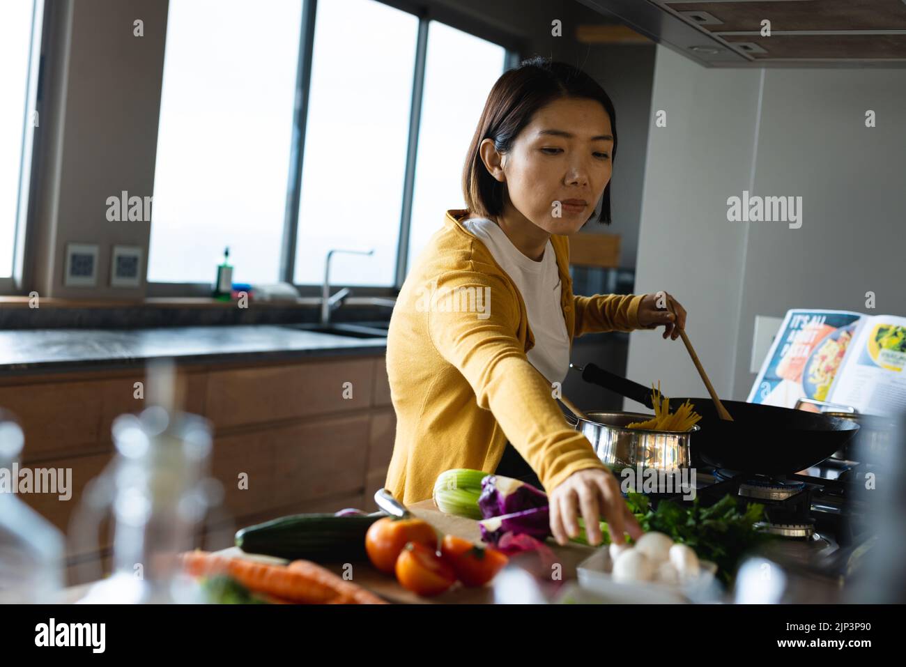 Happy asian woman preparing dinner, using cookbook in kitchen Stock ...