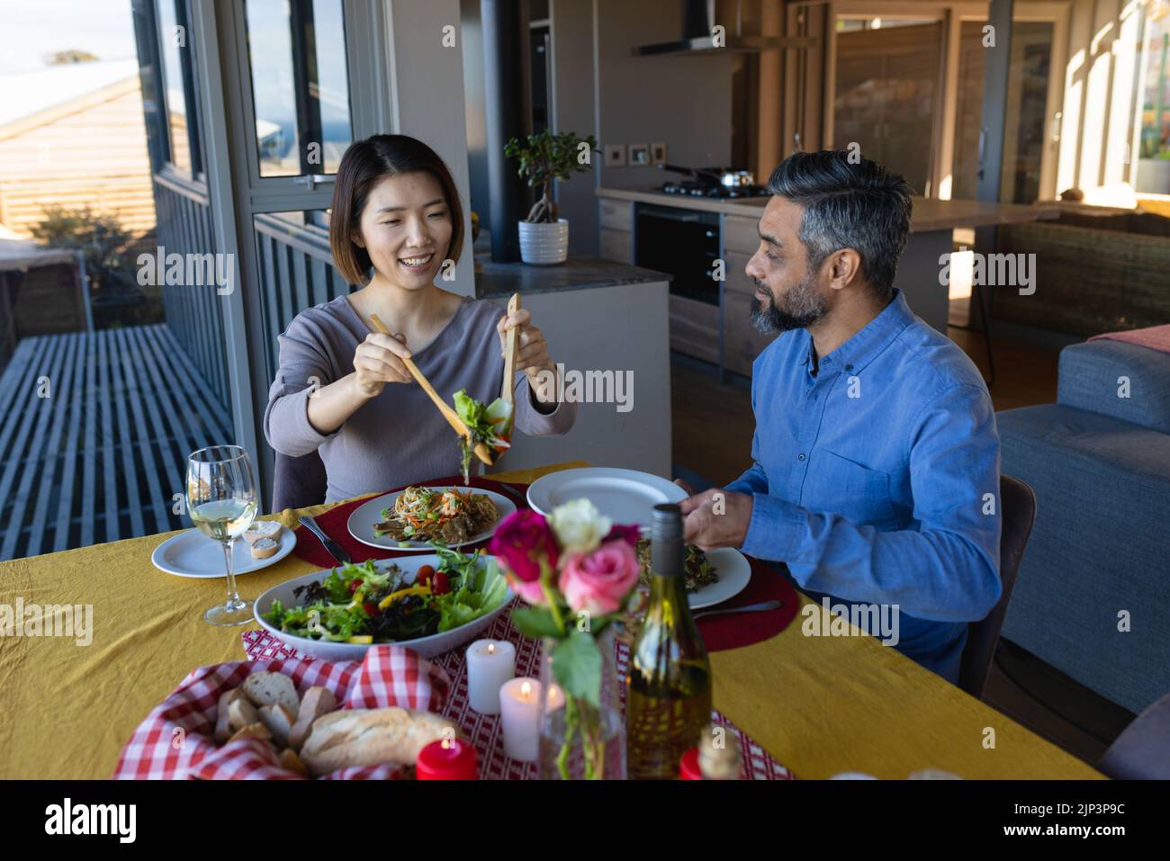 Happy diverse couple sitting at table, eating dinner together Stock ...