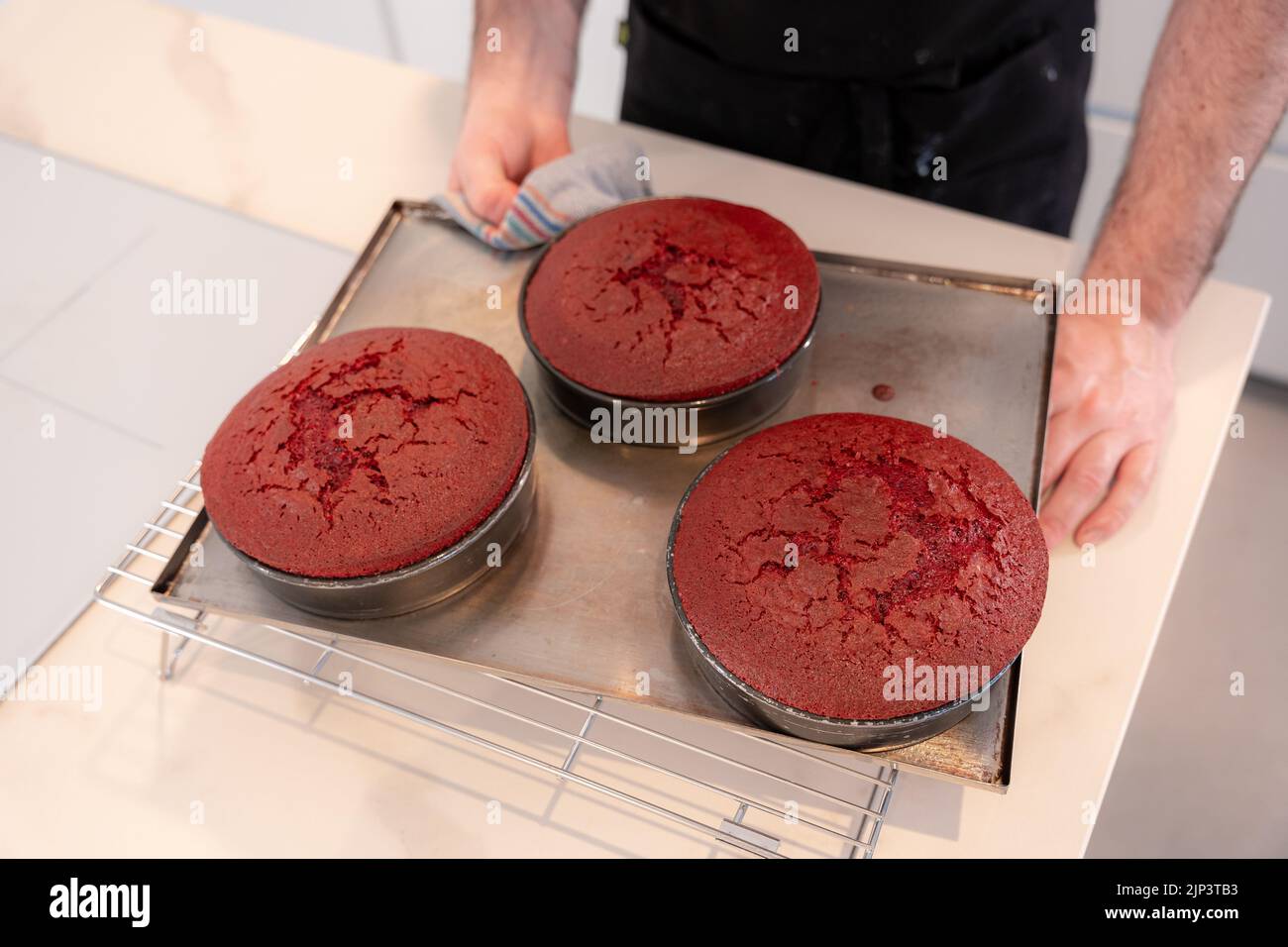 Three freshly baked sponge cakes in the oven molds, hands of a man ...
