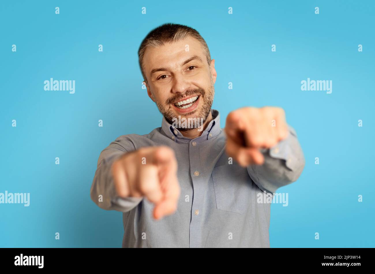 Cheerful Middle Aged Man Pointing Fingers At Camera, Blue Background ...