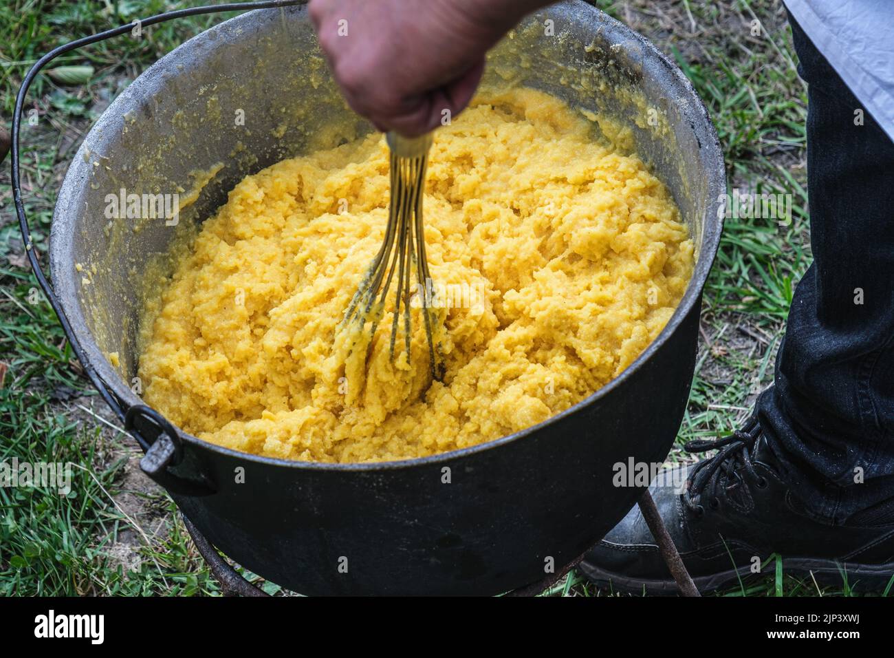 a man chews polenta in a cauldron on the open fire Stock Photo - Alamy