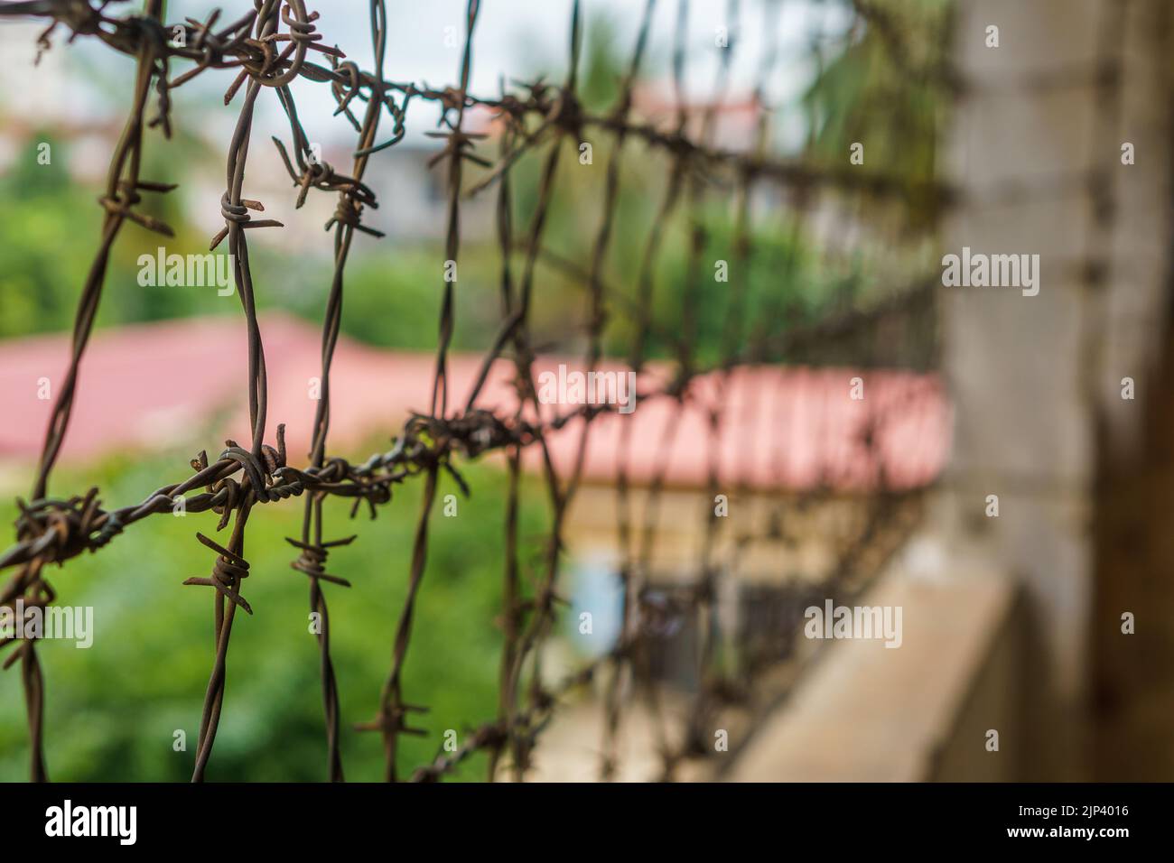 Barbed wire covering a window with a prison building in the background ...