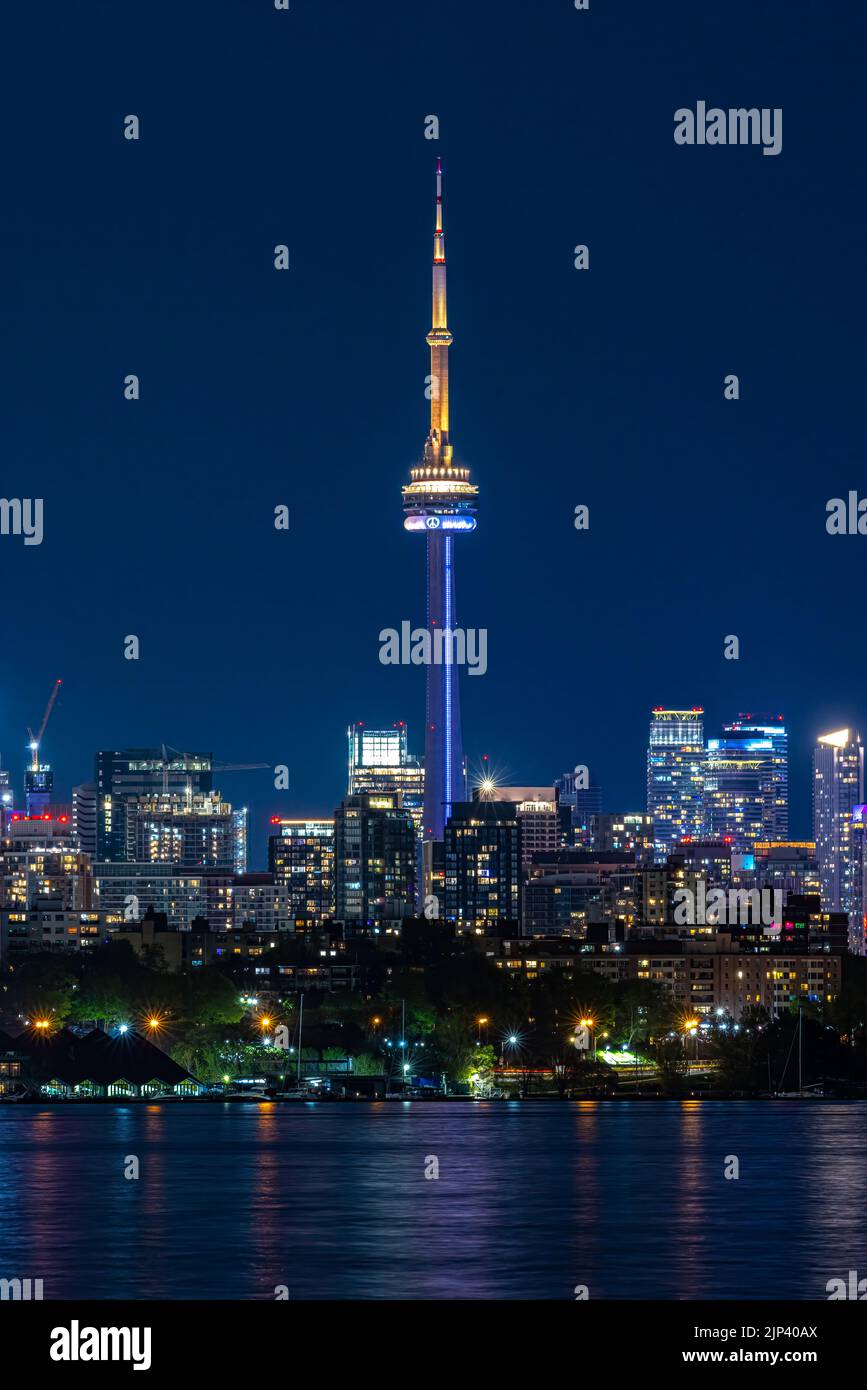A vertical shot of Ontario Lake with CN Tower and skyscrapers at night ...