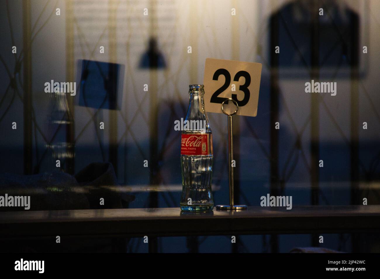 An empty glass Coca-Cola bottle next to a sign indicating table number ...