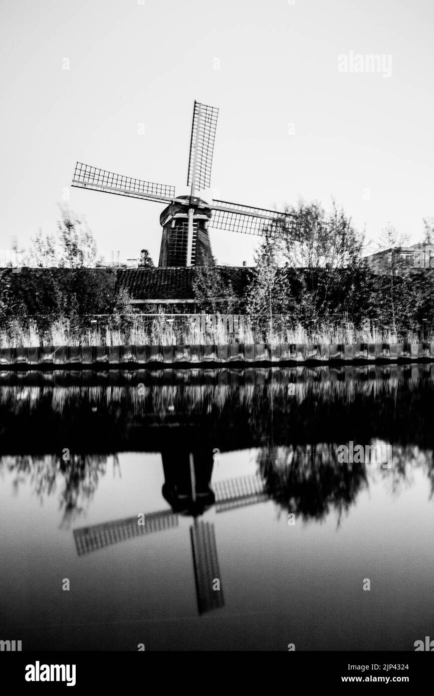 A vertical grayscale shot of a traditional windmill with reflection in ...