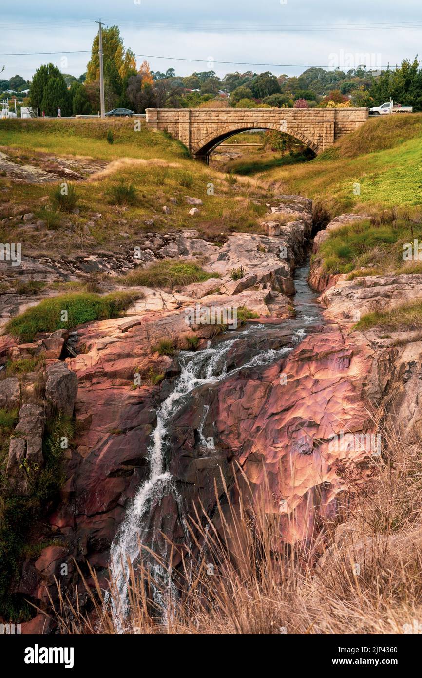 A vertical shot of water flowing on small rocks with a brick stone ...