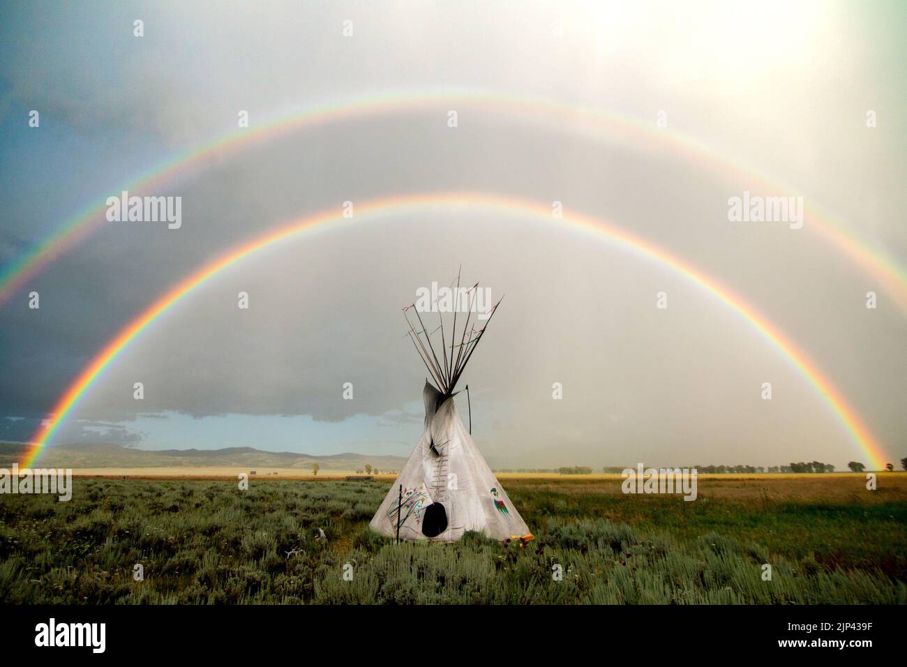 A white conical tent resembling a tipi against the rainbow background ...