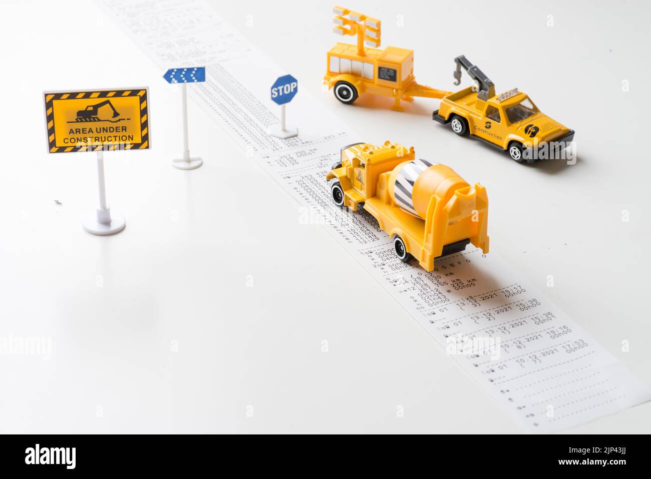 A view of plastic toys of yellow construction cars against a white ...