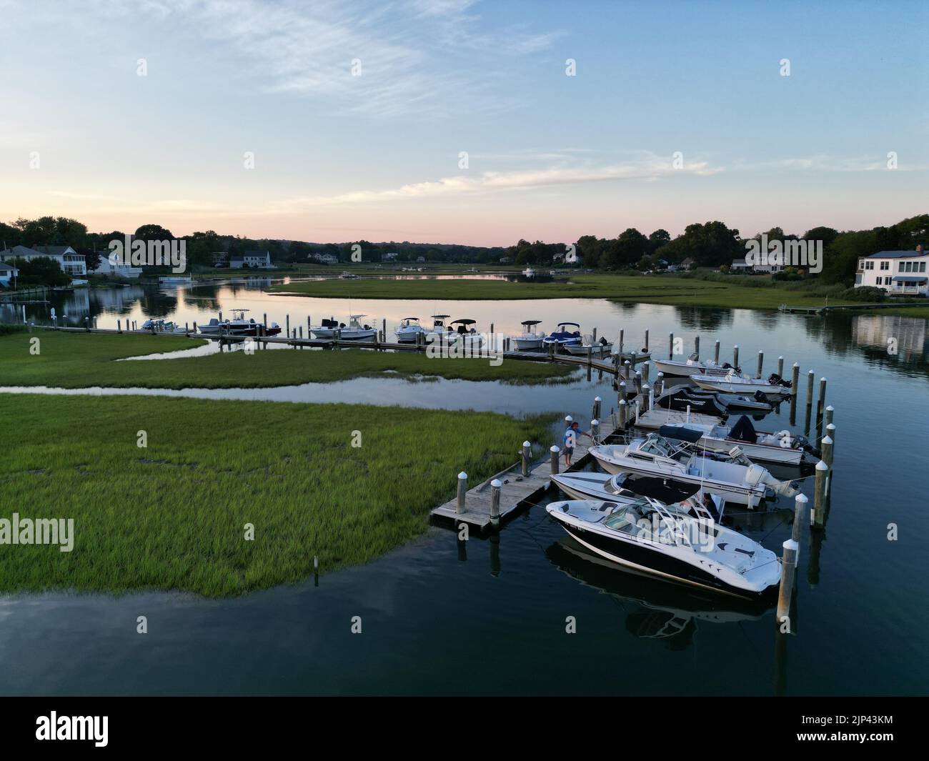 A port with boats and houses on the coast during sunset in Old Saybrook ...