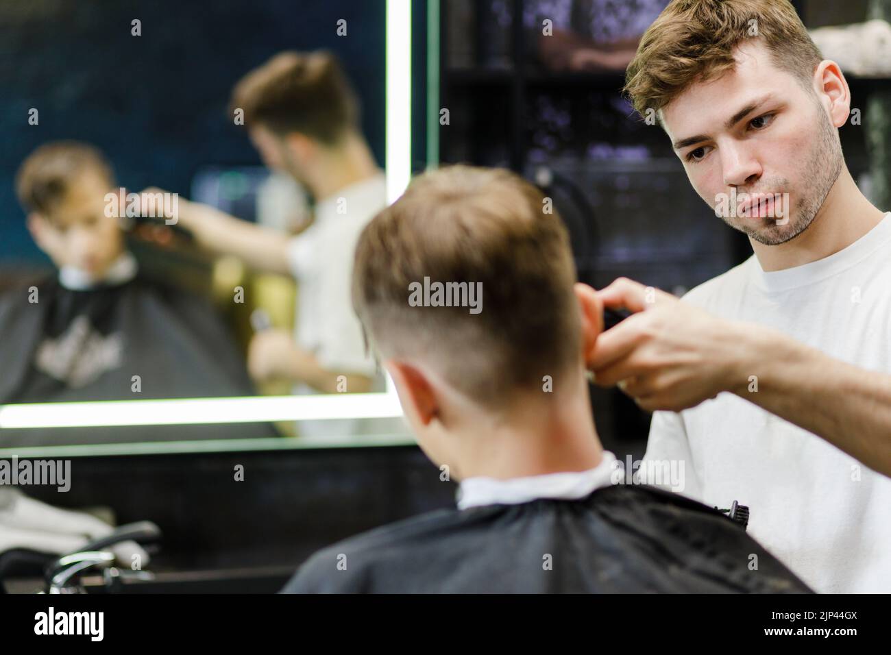 Young male barber trimming hair of the teenage boy in barbershop Stock ...