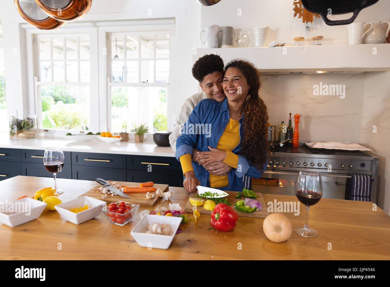 Happy Biracial Couple Preparing Food And Embracing In Kitchen Stock