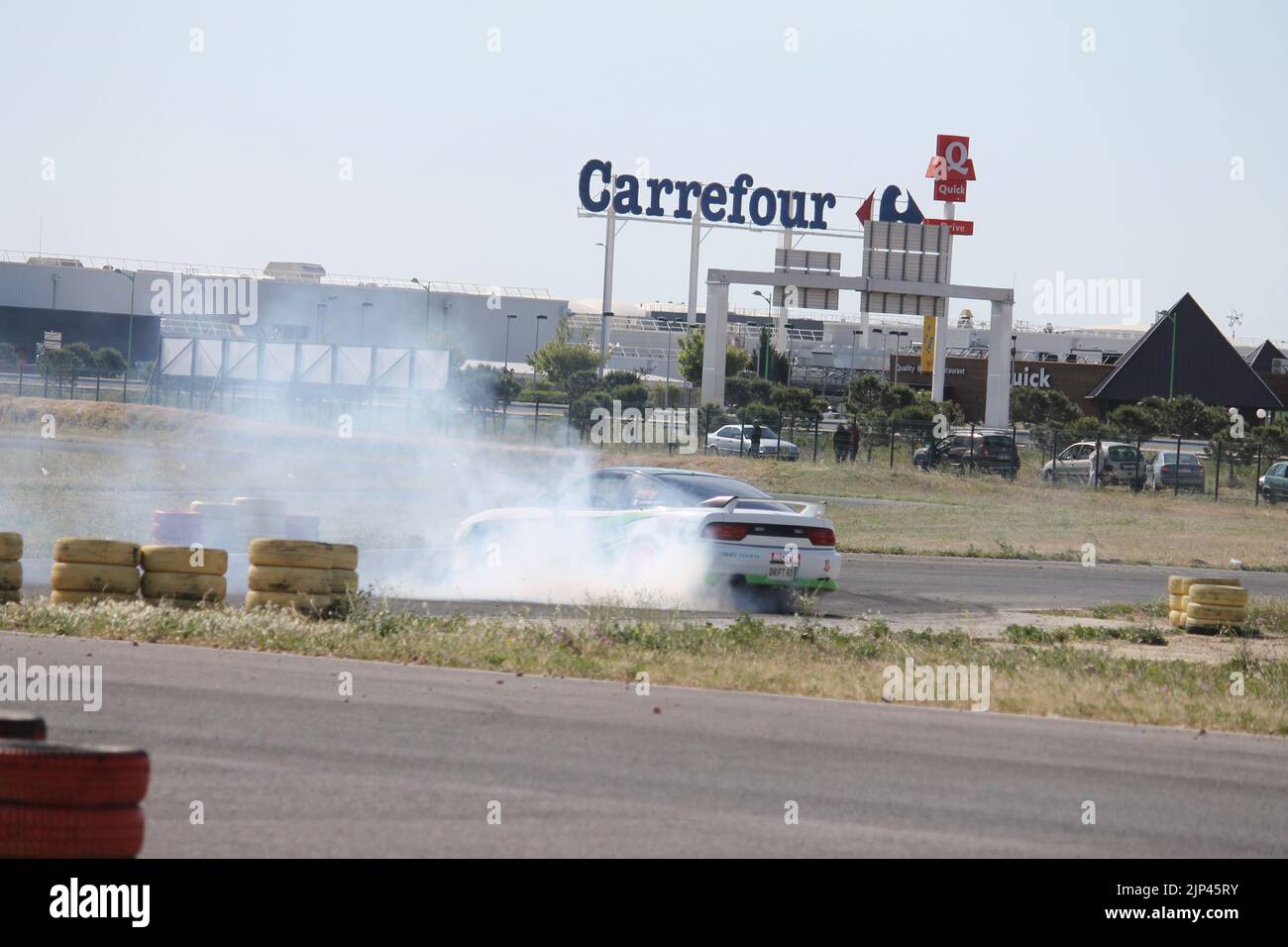 A drifting white car making smog around Carrefour background Stock ...