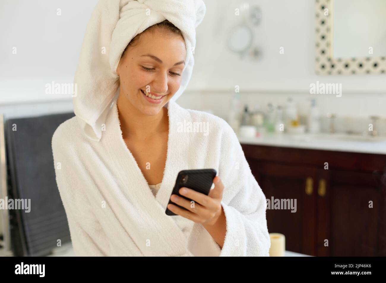 Happy caucasian woman wearing robe, using smartphone in bathroom Stock ...