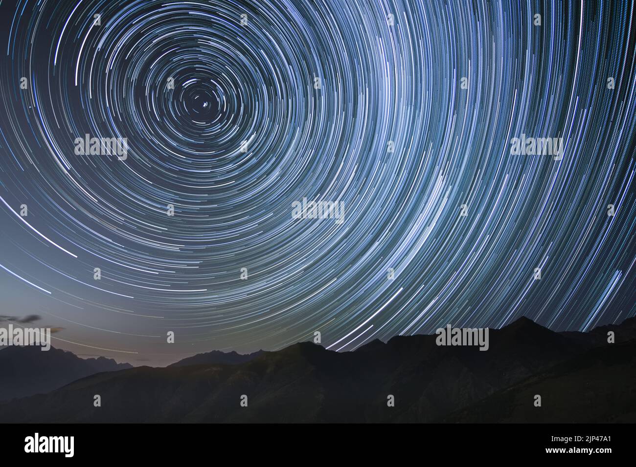 silhouetted mountains with circumpolar star trails in northern sky ...