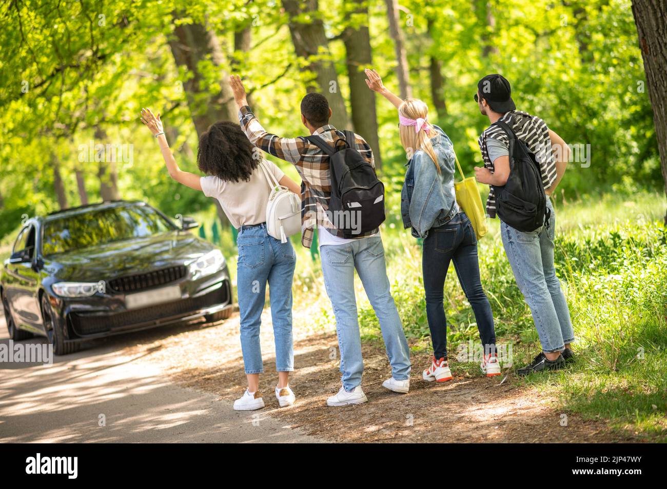 Group of young people hitchiking on the road Stock Photo - Alamy