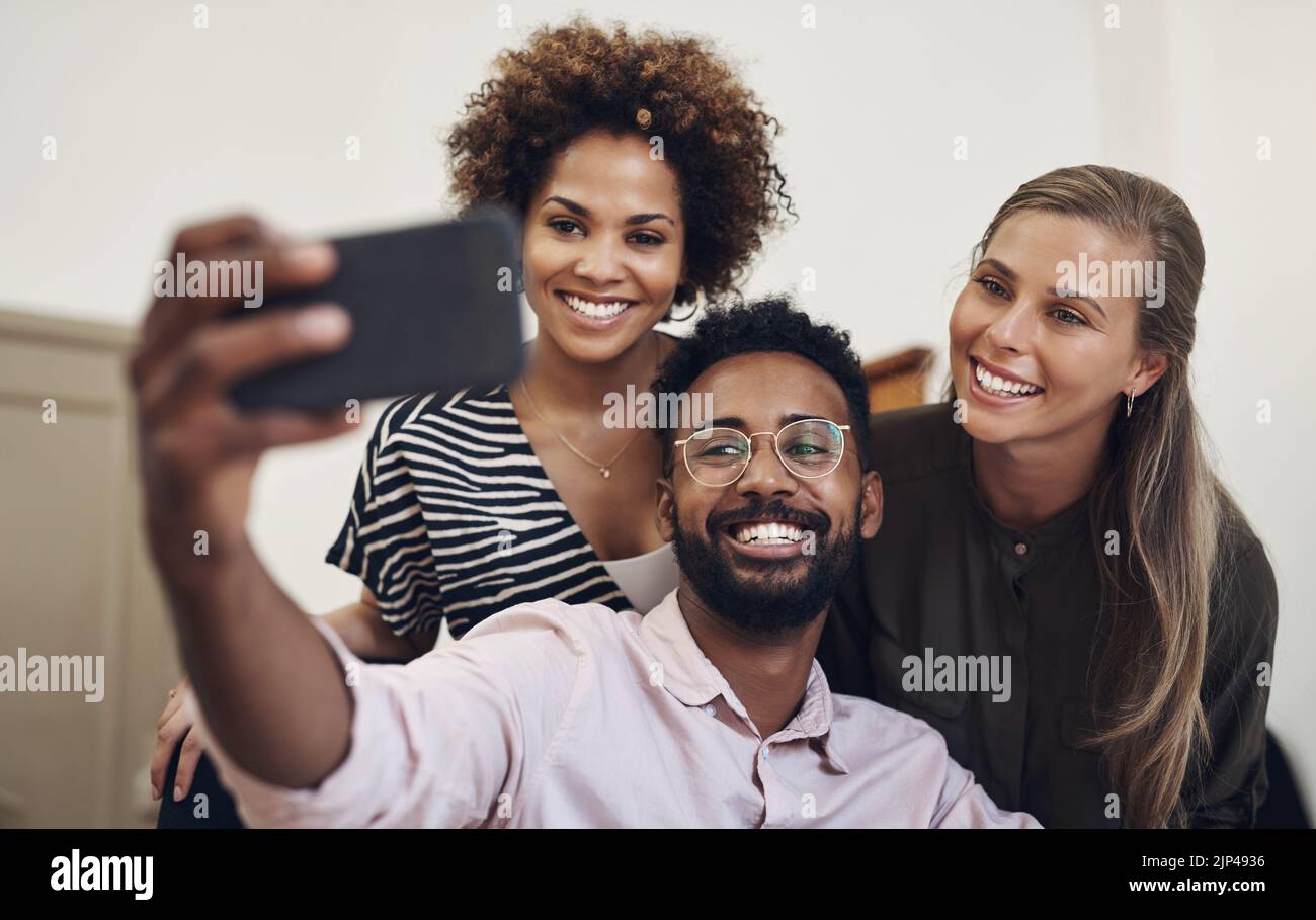Group of office friends taking a happy selfie using a phone in business ...