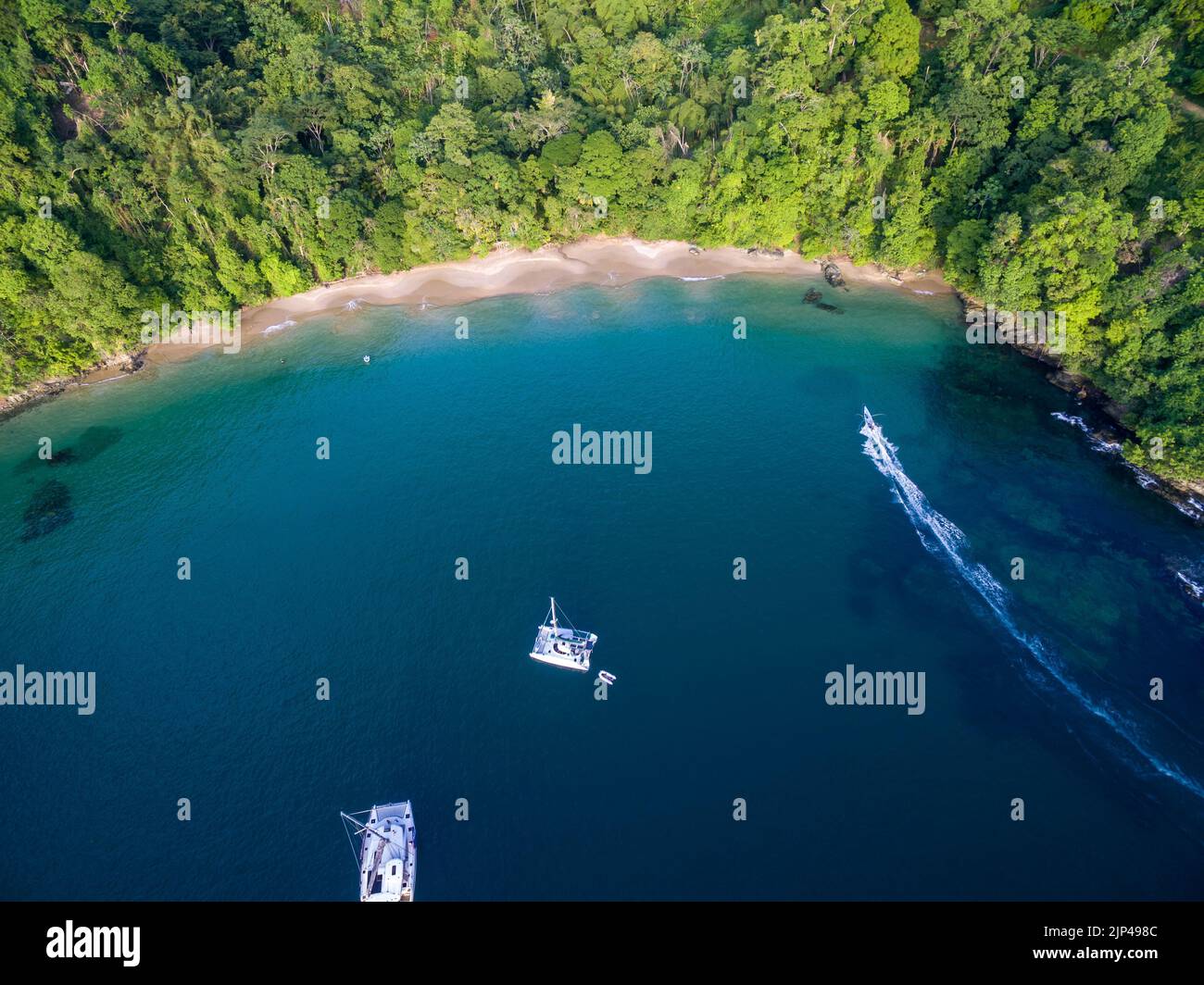 Yachts anchoring in Caribbean bay with boat driving though scenery ...