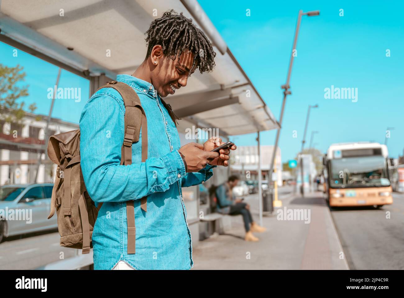 Guy looking at smartphone standing sideways to camera Stock Photo - Alamy