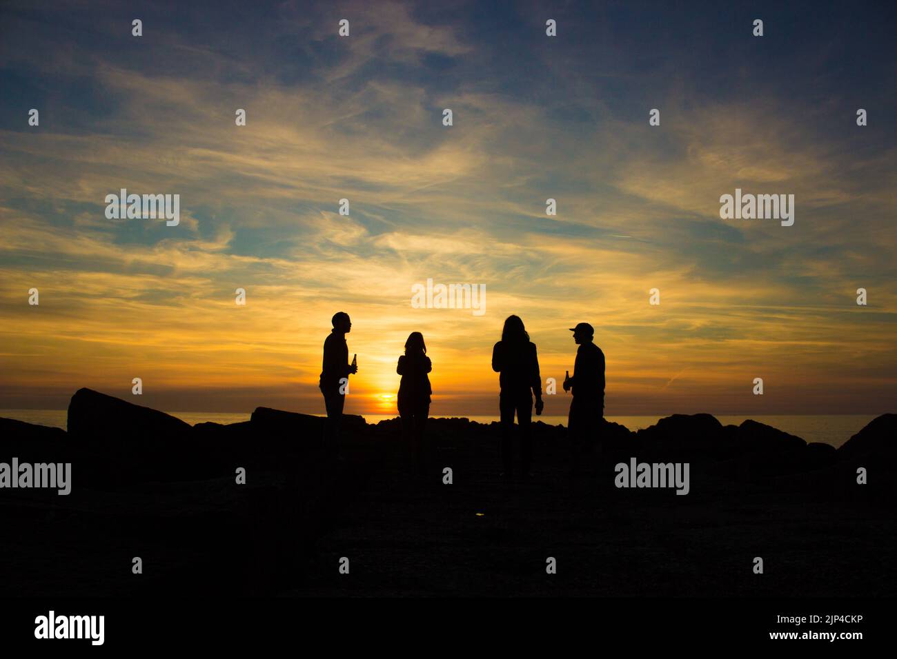 The silhouettes of four friends enjoying the sunset in Thy, Denmark ...