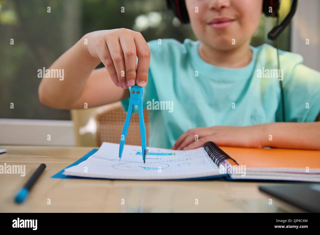 Details: hand of a schoolboy in audio headset using geometric compass ...