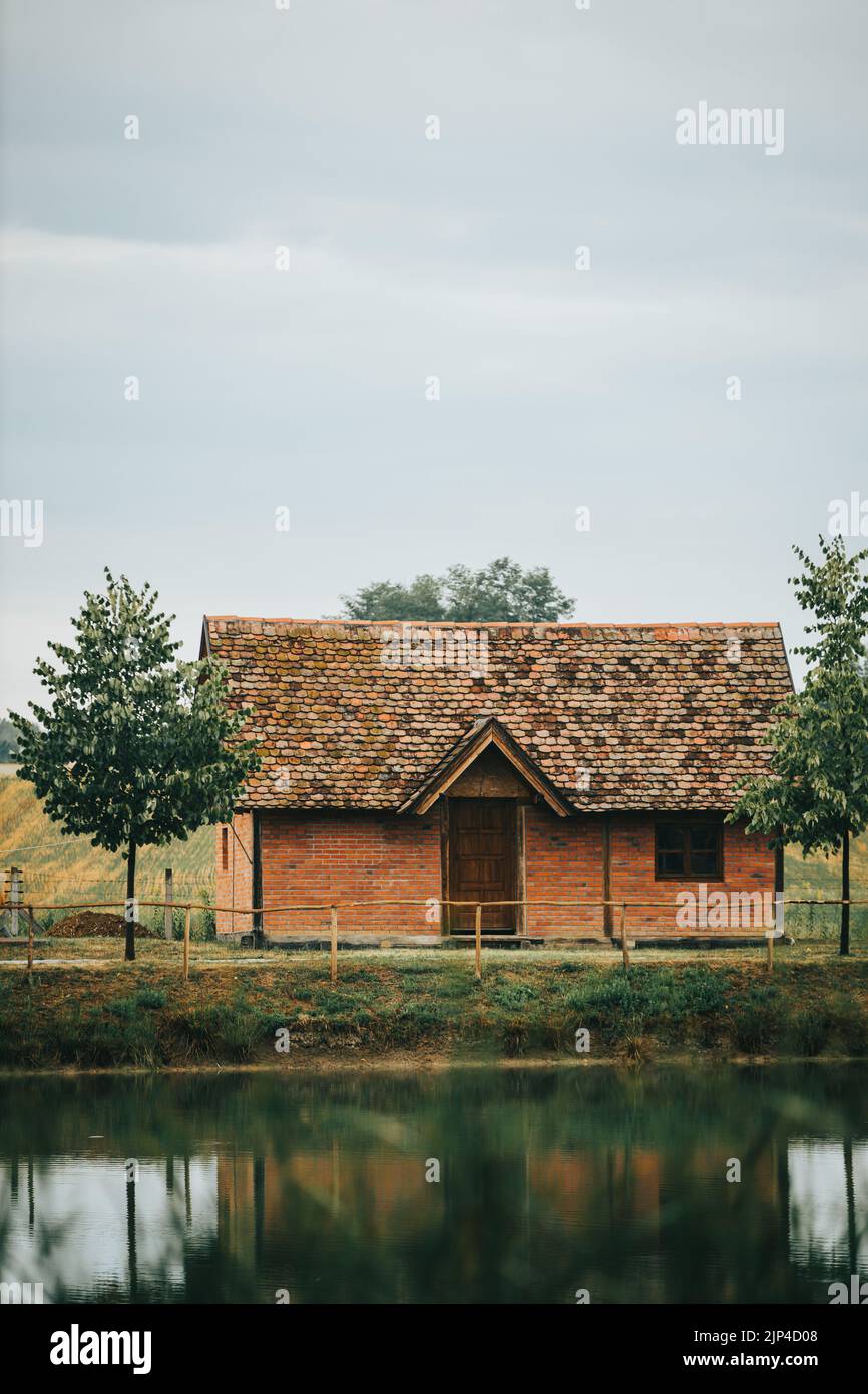 A vertical shot of a brick country house by a lake Stock Photo - Alamy