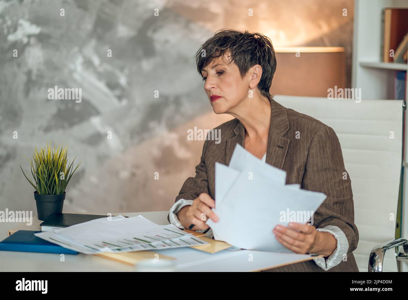 Short-haired businesswoman sitting in the office and working with papers Stock Photo - Alamy