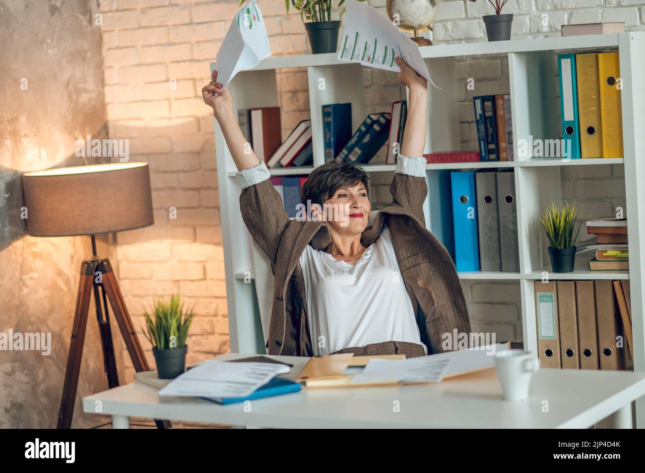 Short-haired mid aged woman sitting at the table in the office and ...