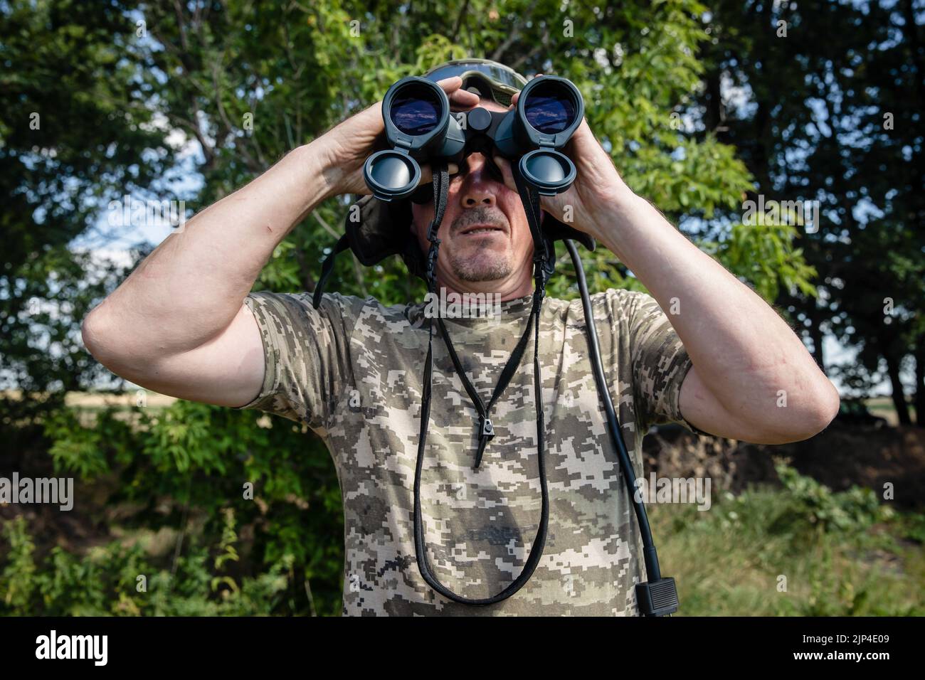 A soldier of the armed forces of Ukraine looks through binoculars ...