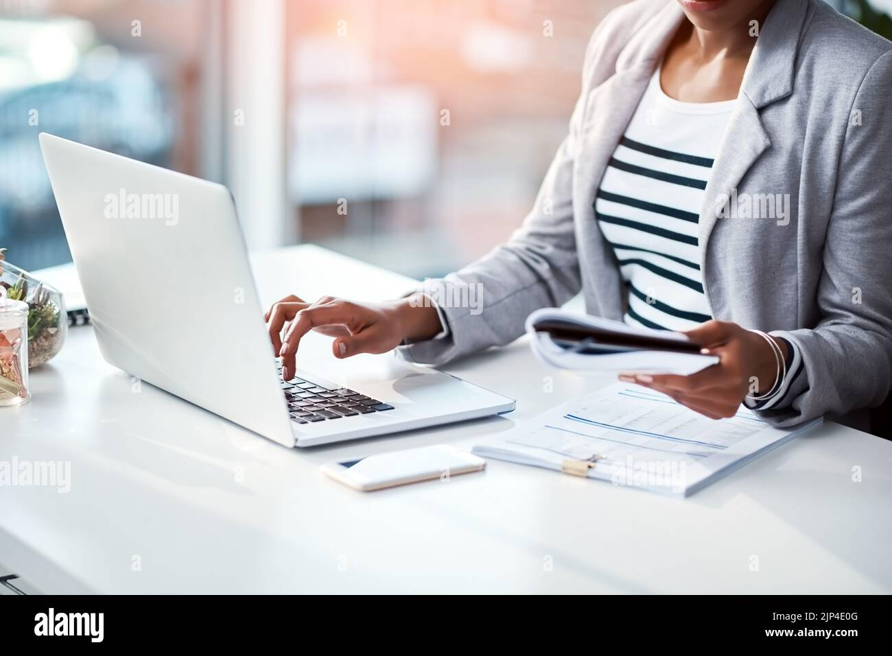 Business woman typing on laptop, reading from notebook and planning a ...